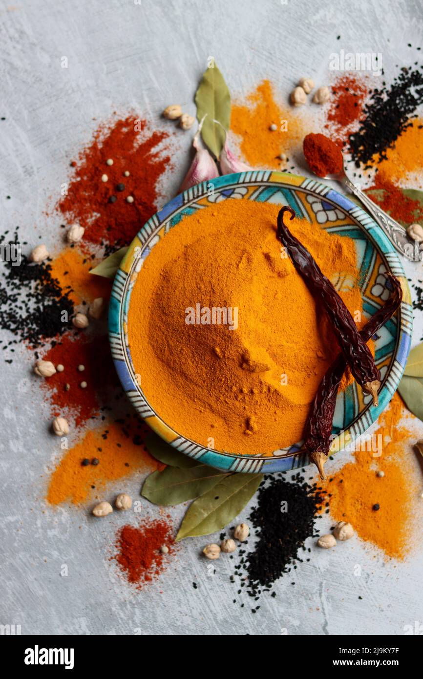 Colorful still life with turmeric powder on blue handmade plate. Close ...