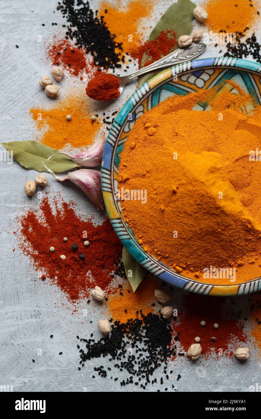 Colorful still life with turmeric powder on blue handmade plate. Close ...