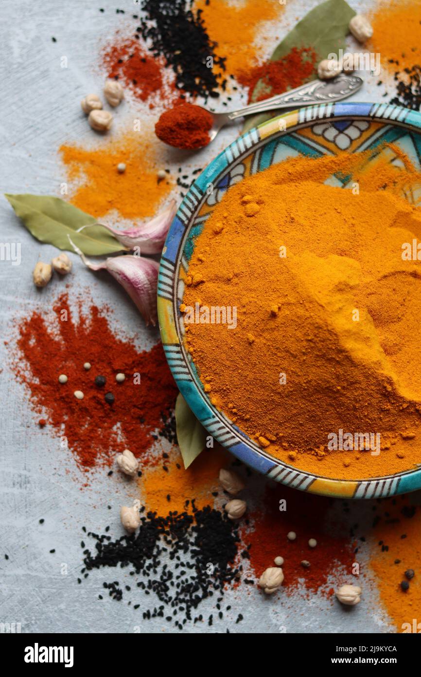 Colorful still life with turmeric powder on blue handmade plate. Close ...