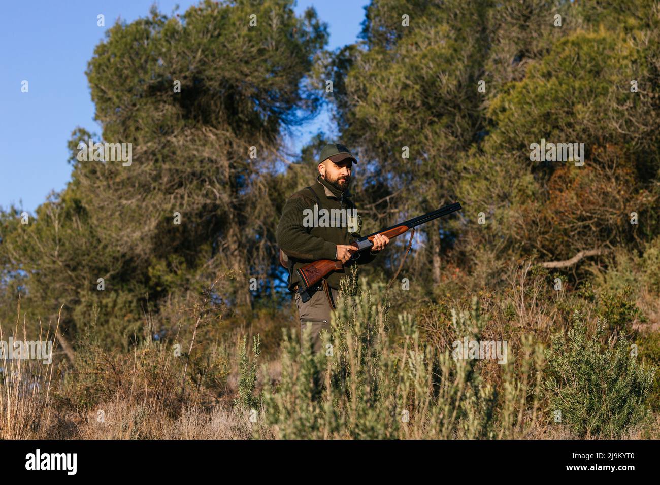 Hunter walking among outdoor grass with gun Stock Photo - Alamy