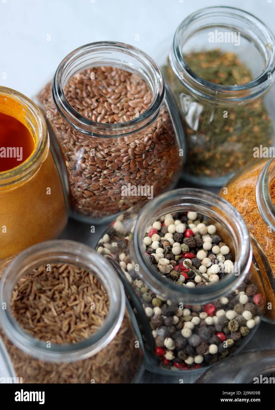 Small glass jars with different spices. Peppercorn, cardamom, turmeric ...