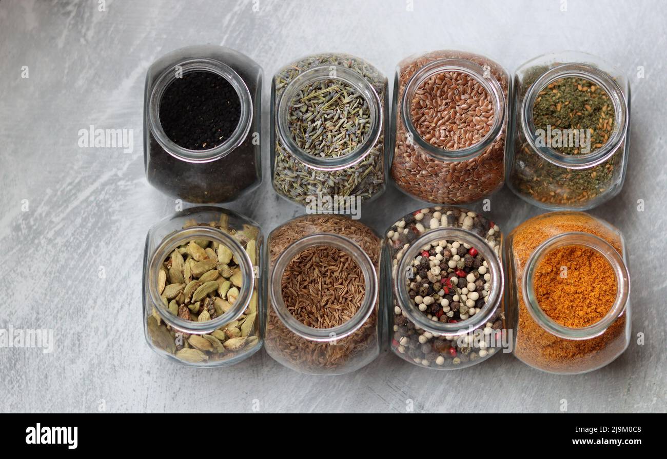 Small glass jars with different spices. Peppercorn, cardamom, turmeric ...