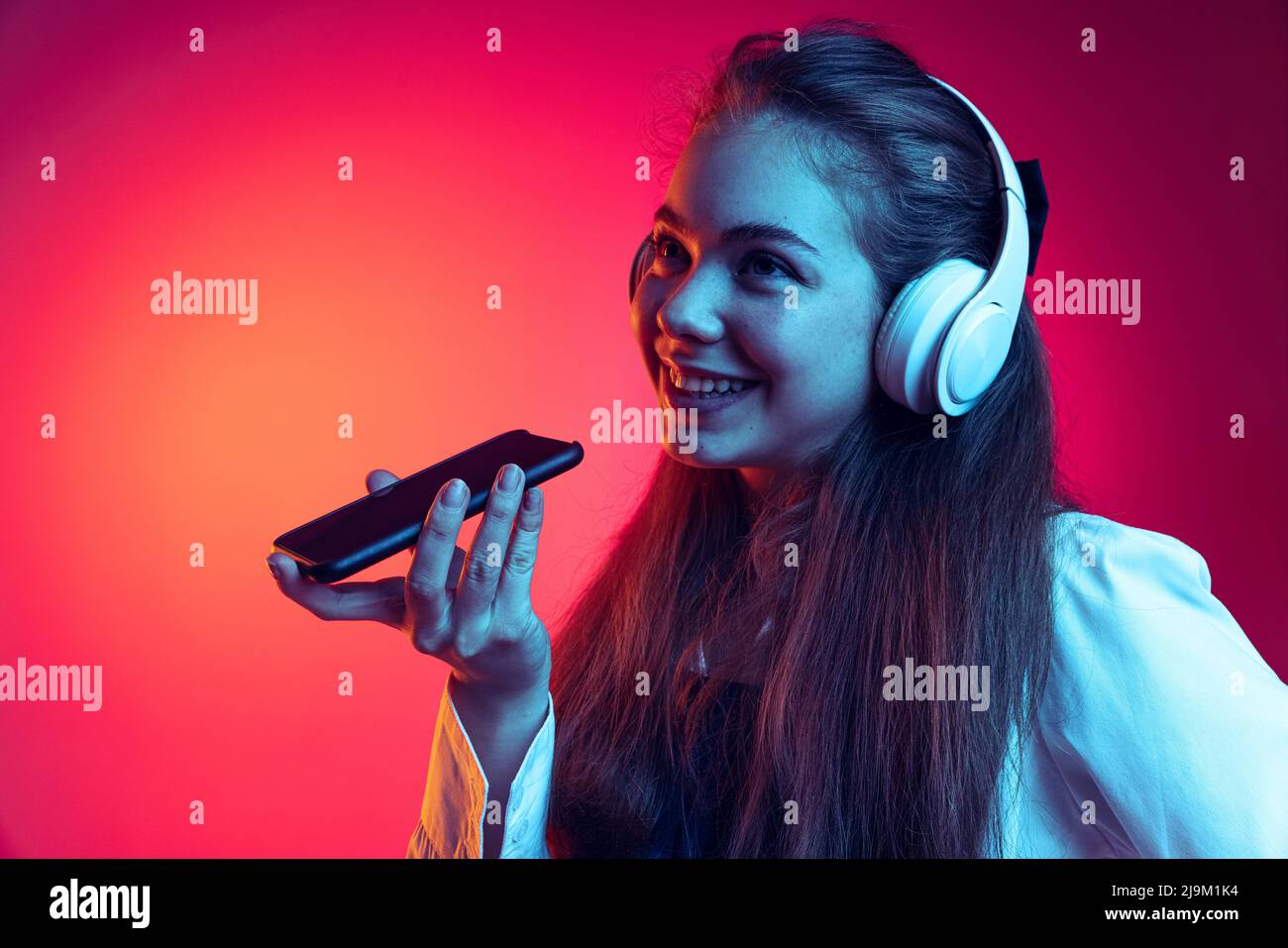 Portrait of young cheerful girl, student in headphones recording voice ...