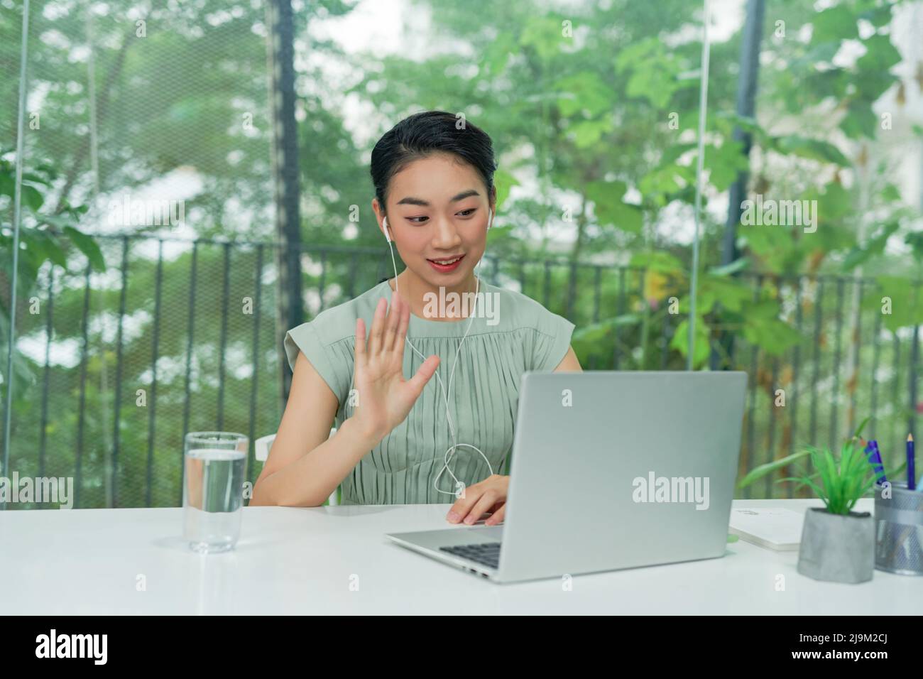 Head shot happy young woman sitting at white desk, looking at camera ...