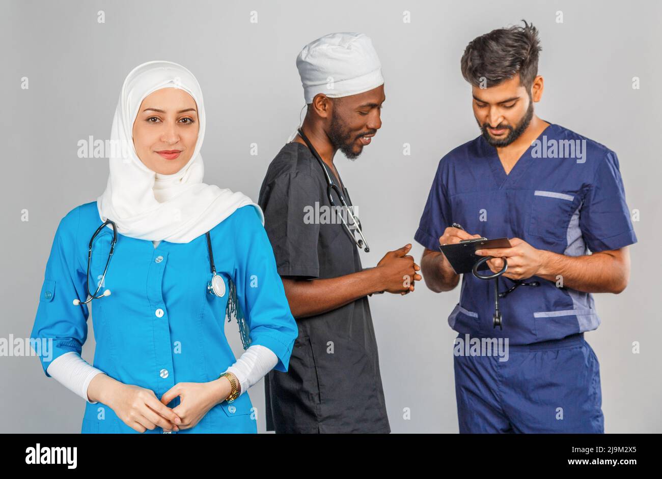 Group of paramedics smiling over gray background. muslim doctor woman ...