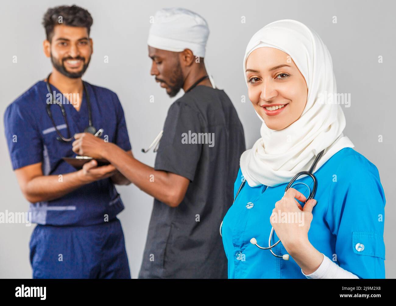 Group of paramedics smiling over gray background. muslim doctor woman ...