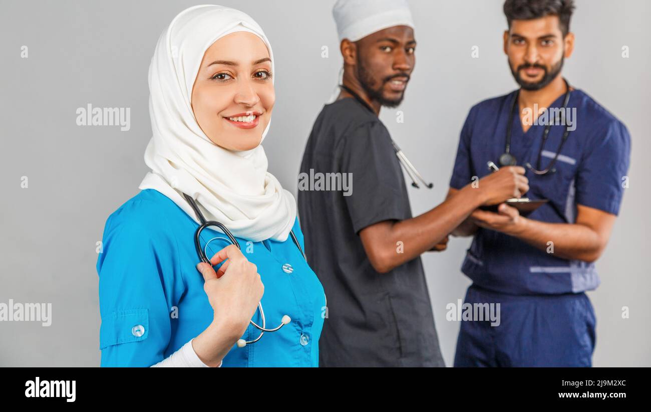 Group of paramedics smiling over gray background. muslim doctor woman ...