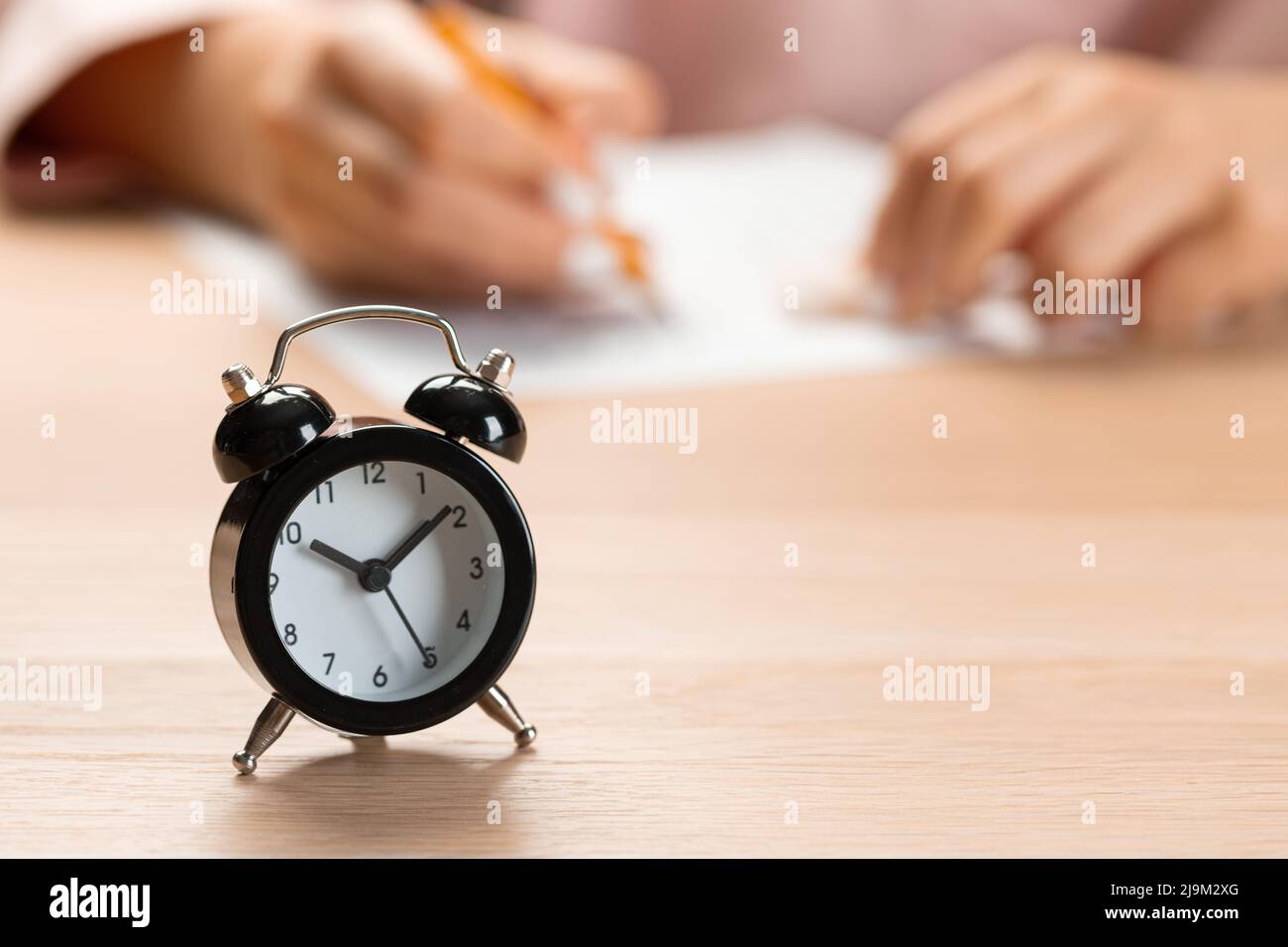 alarm clock with time running out. Students hands to take exams, write ...