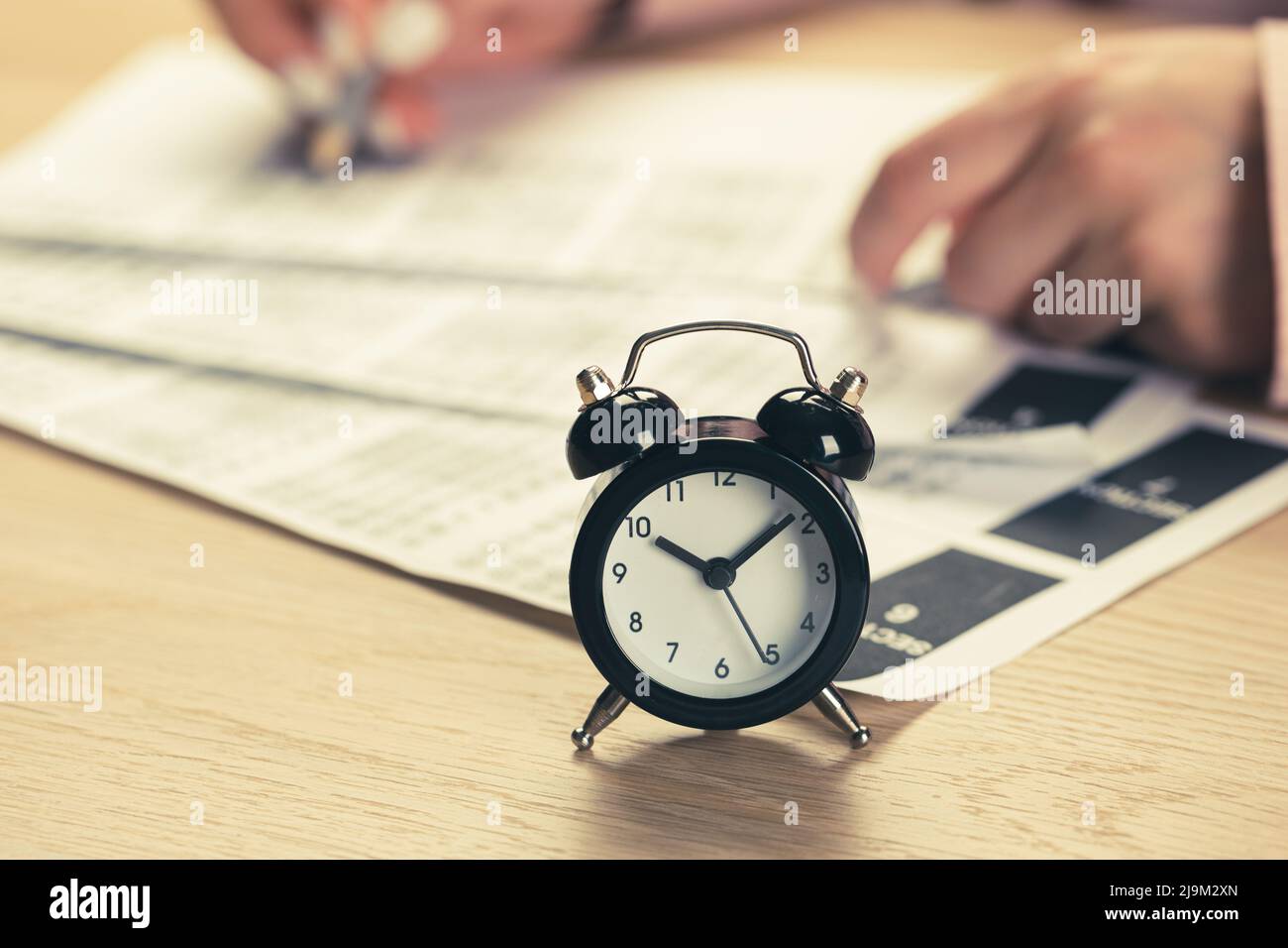 alarm clock with time running out. Students hands to take exams, write ...