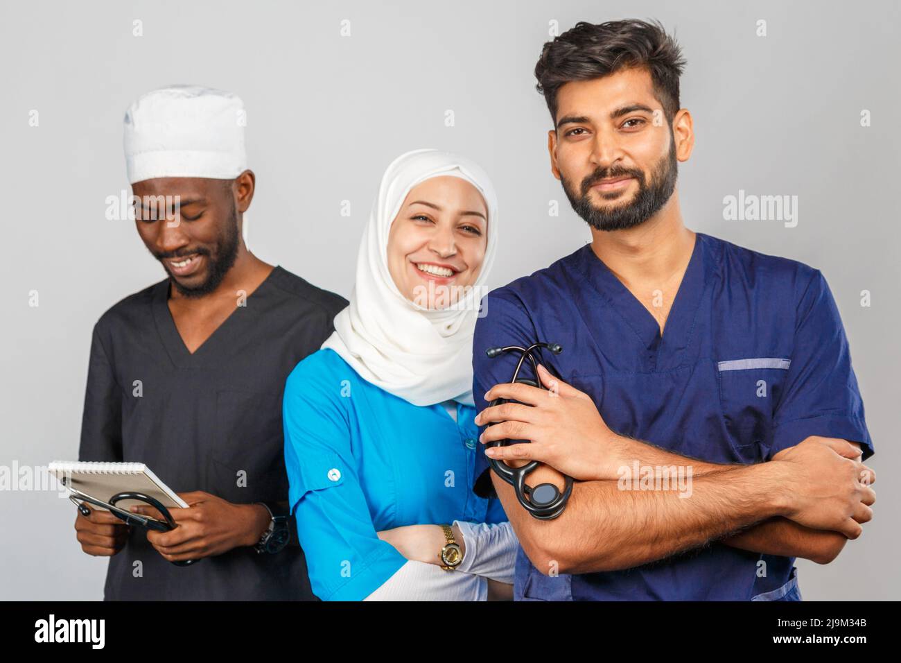 Group of paramedics smiling over gray background. muslim doctor woman ...