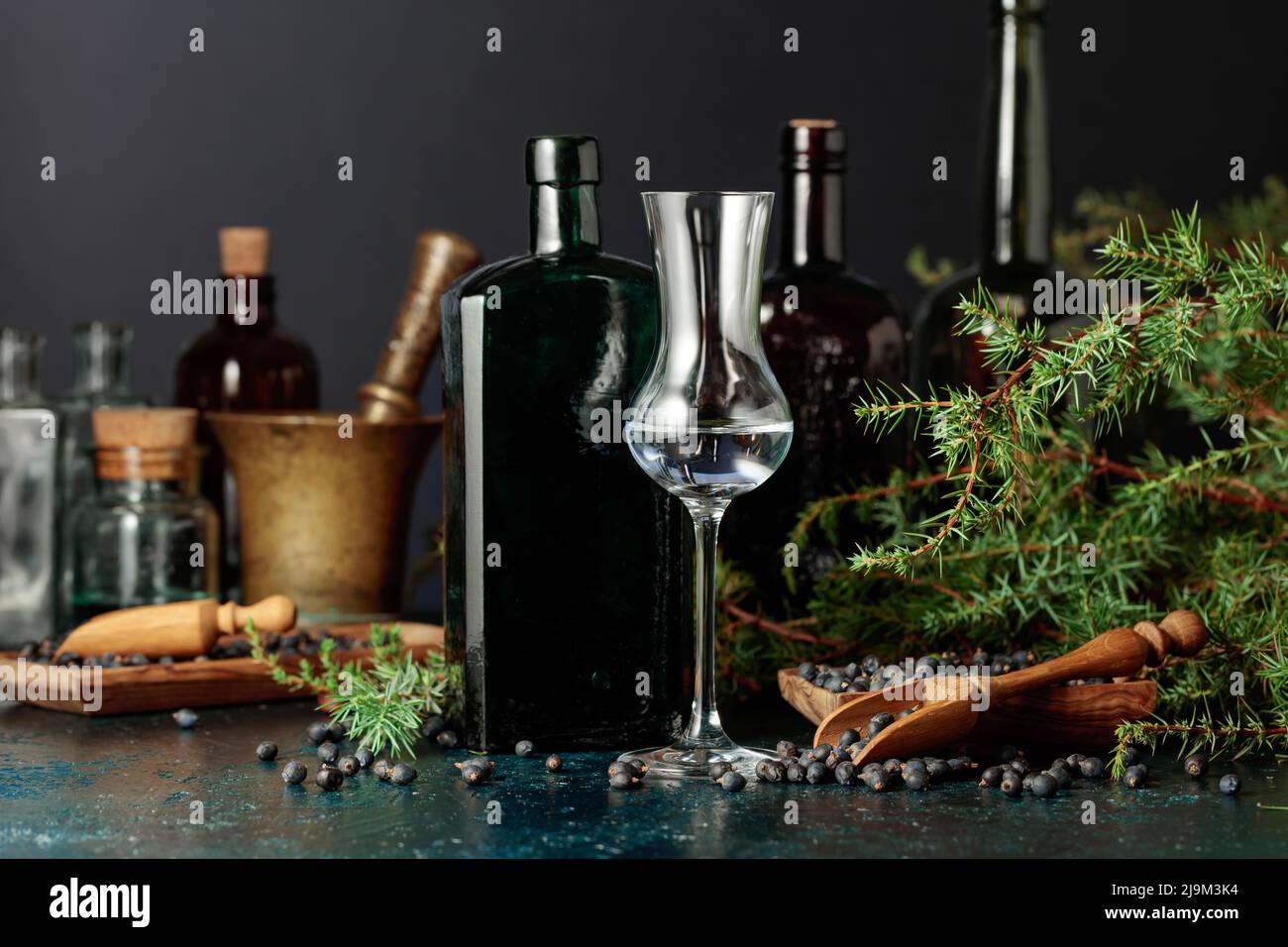 Gin with juniper seeds and branches on an old table. In the background ...