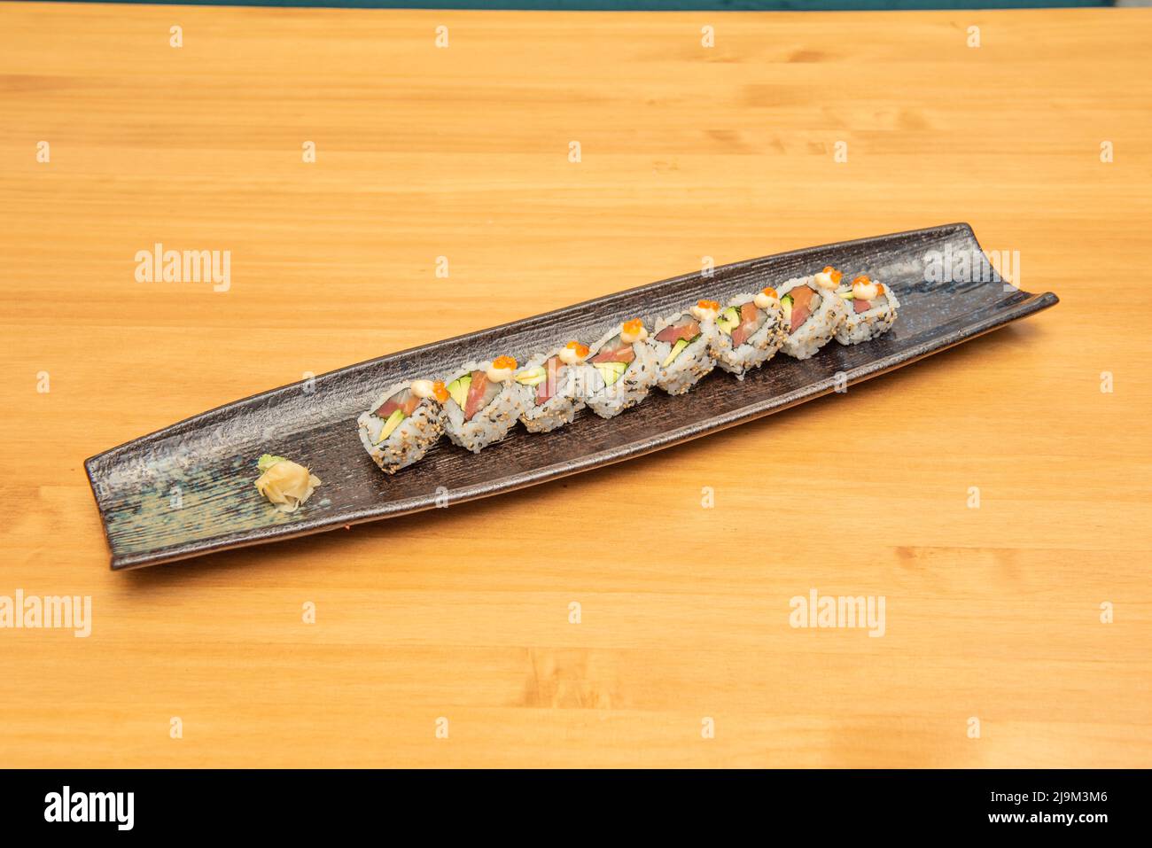 Modern style black tray with a portion of salmon uramaki sushi with ...