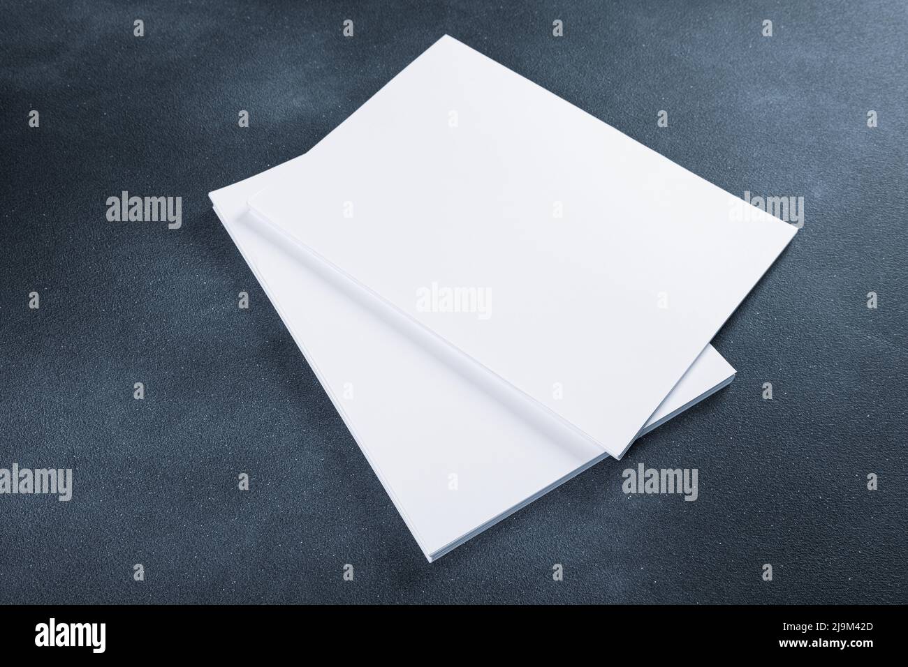 White business card sheet of paper a4 stack on a dark table. cold toned ...