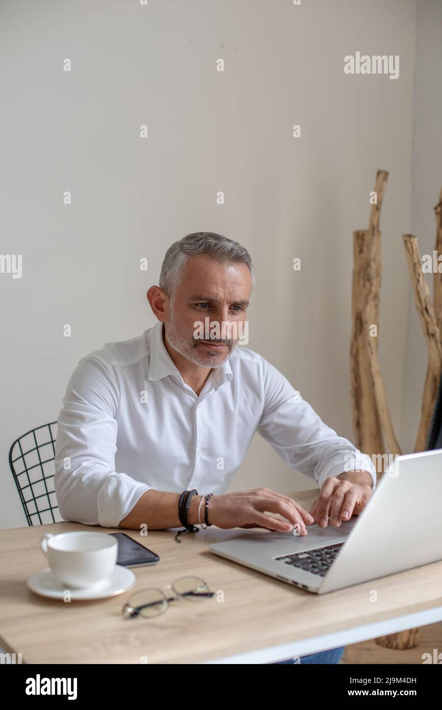 Man working on laptop sitting at table Stock Photo - Alamy
