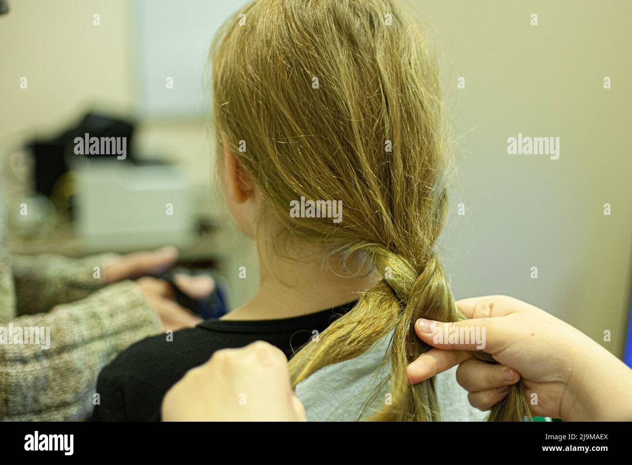 The girl is braiding a braid. The hair of the girl is styled by the ...