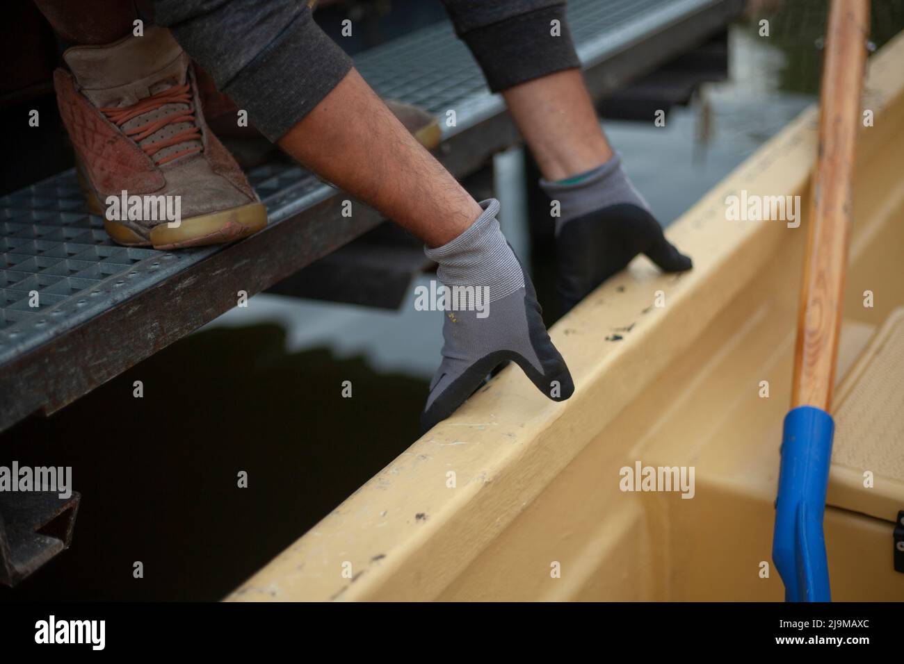 Guy pushes boat away from dock. Details of boat station. Man holds side ...