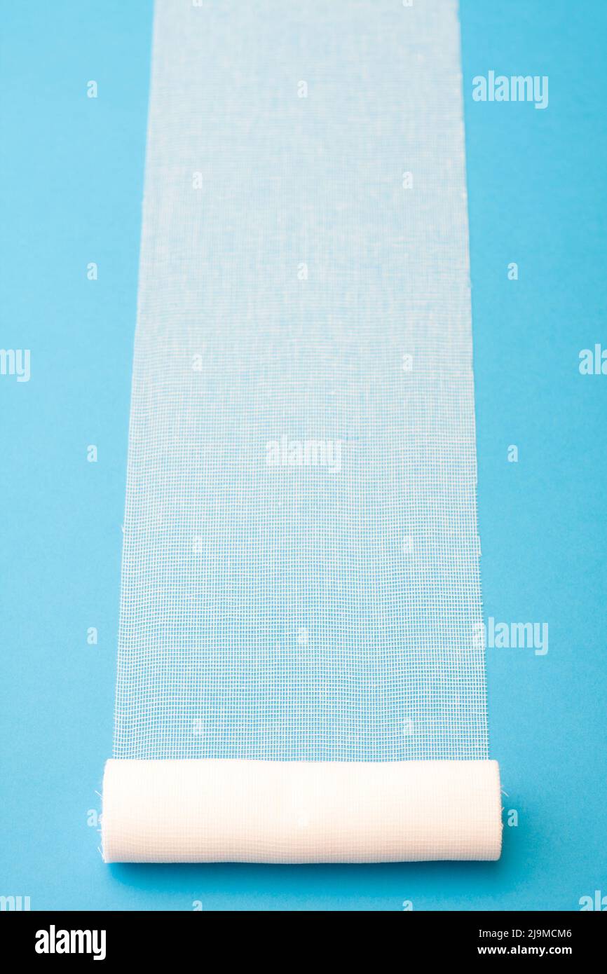 Sterile bandage roll unwound on blue background Stock Photo - Alamy