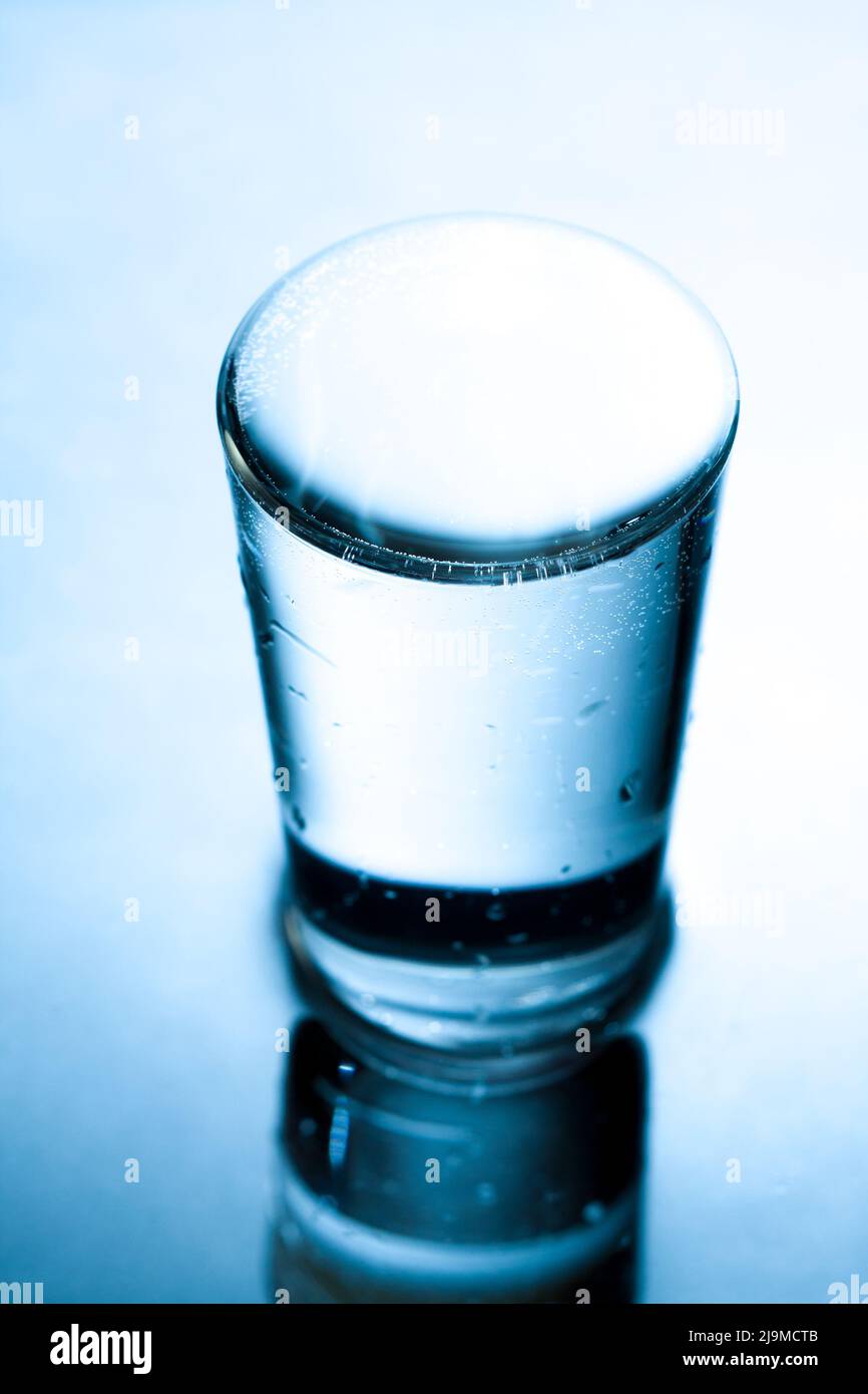 Glass filled to the brim with water in blue monochrome Stock Photo - Alamy