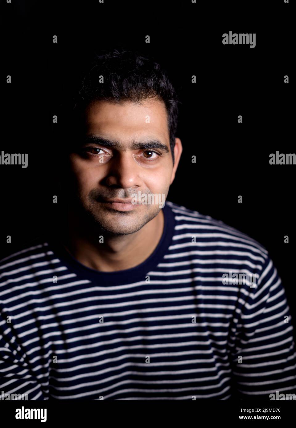 Low key portrait of a handsome Indian man with dark hair, and beard in ...