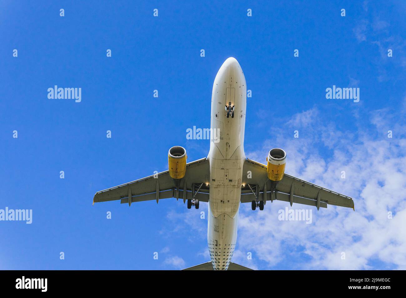 From below of modern aircraft flying against blue sky with white clouds ...