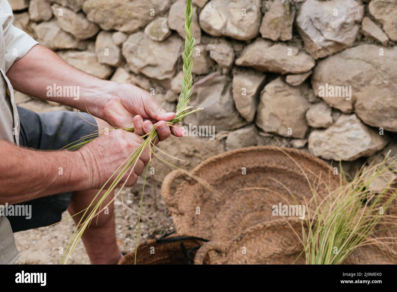 Side view crop mature male artisan in casual clothes weaving basket ...