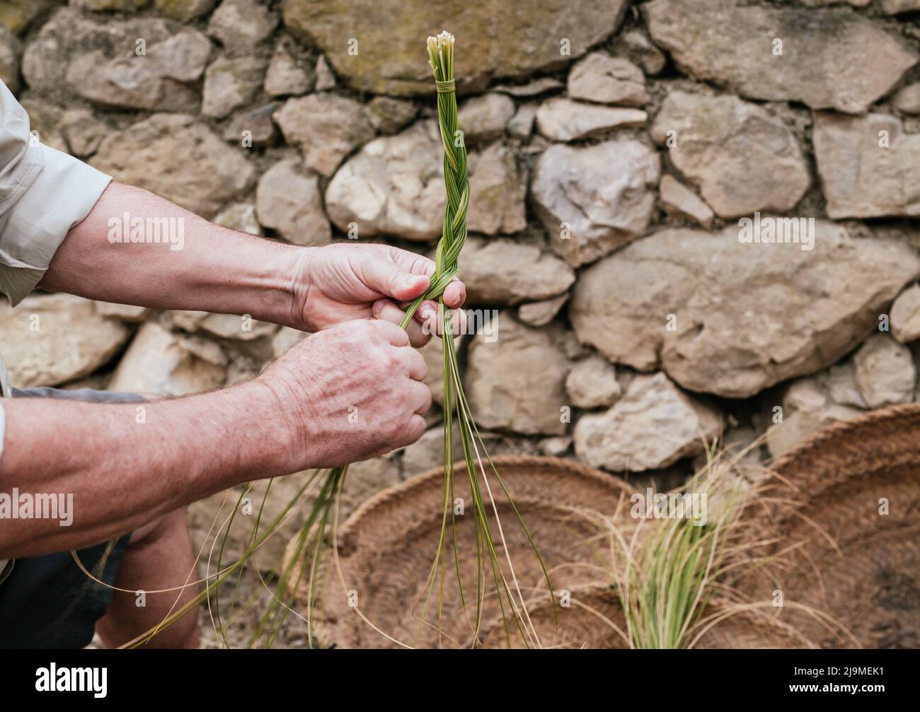 Side view crop mature male artisan in casual clothes weaving basket ...