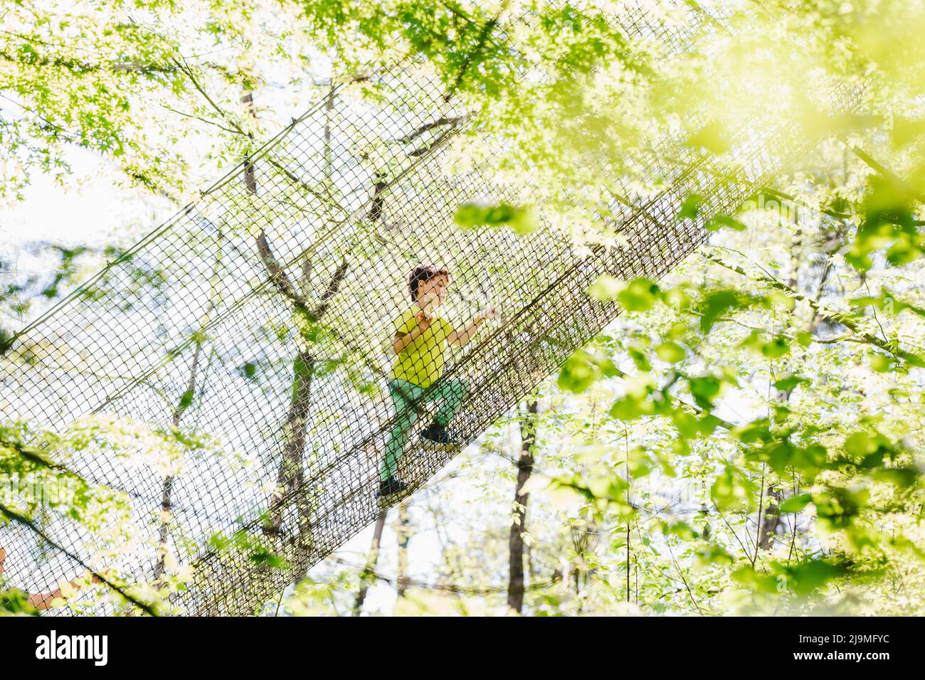 From below of little boy in casual clothes walking up inside net ...