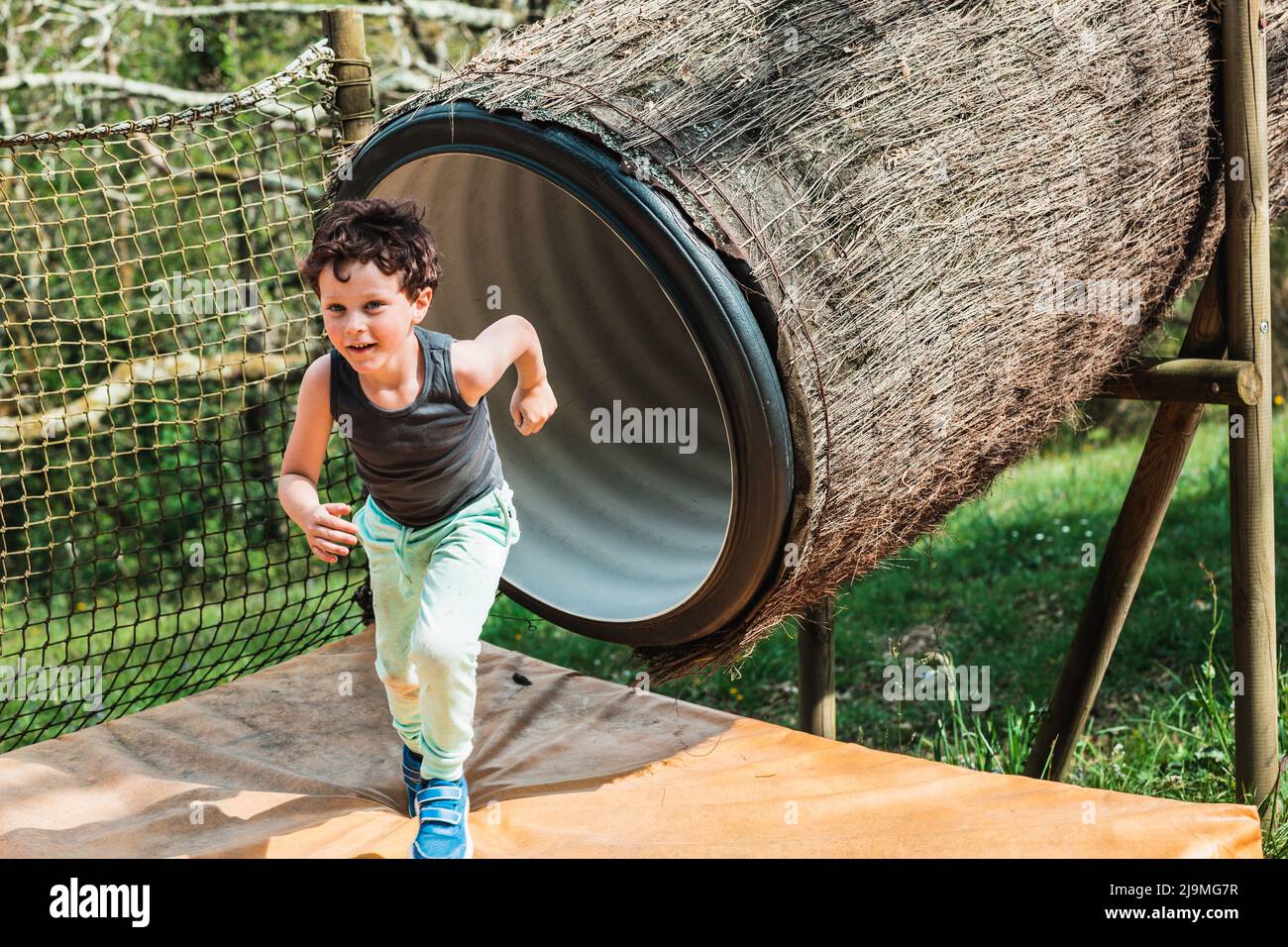 Happy active little boy running after riding tube slide on sunny summer ...