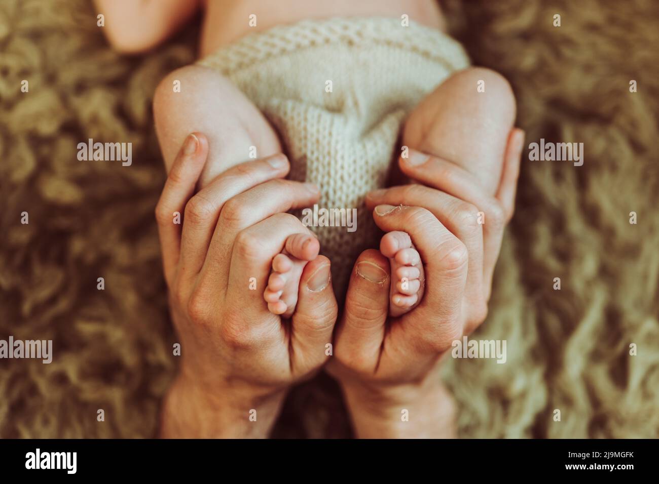From above of crop unrecognizable father caressing small feet of ...