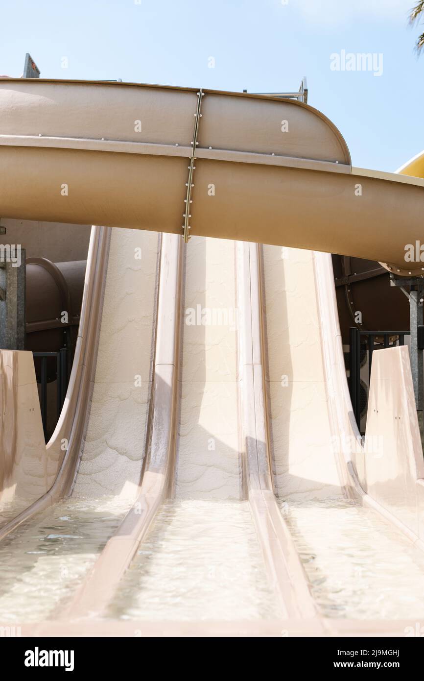 Water flowing down modern slides in outdoor pool of aqua park on sunny ...