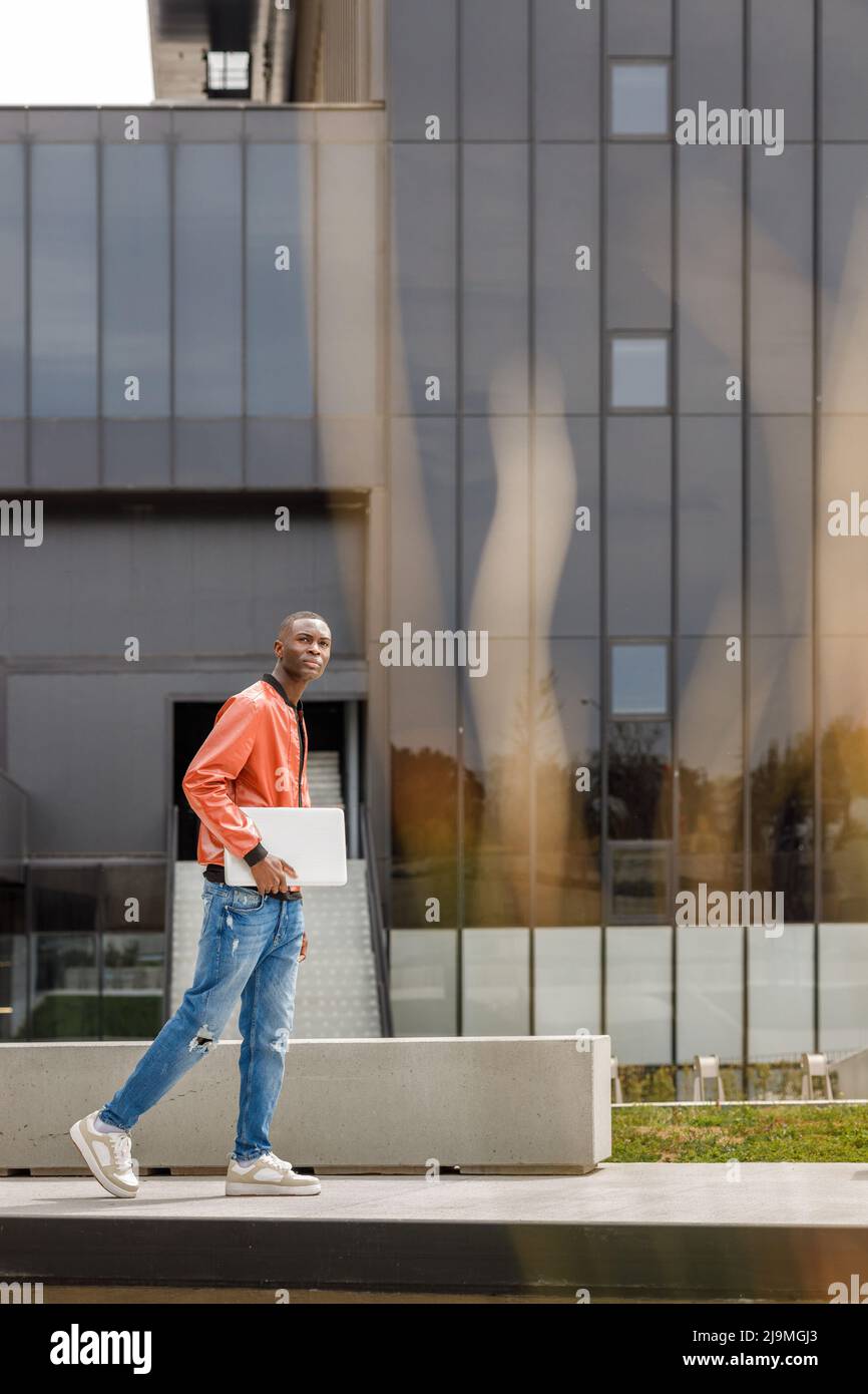 Full length side view of young stylish black male student in trendy ...