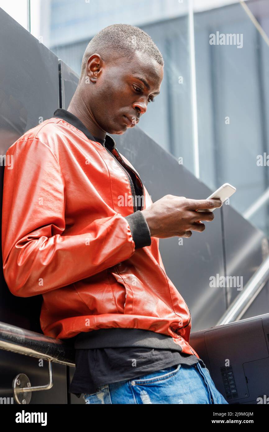 Side view of concentrated young African American guy in trendy red ...