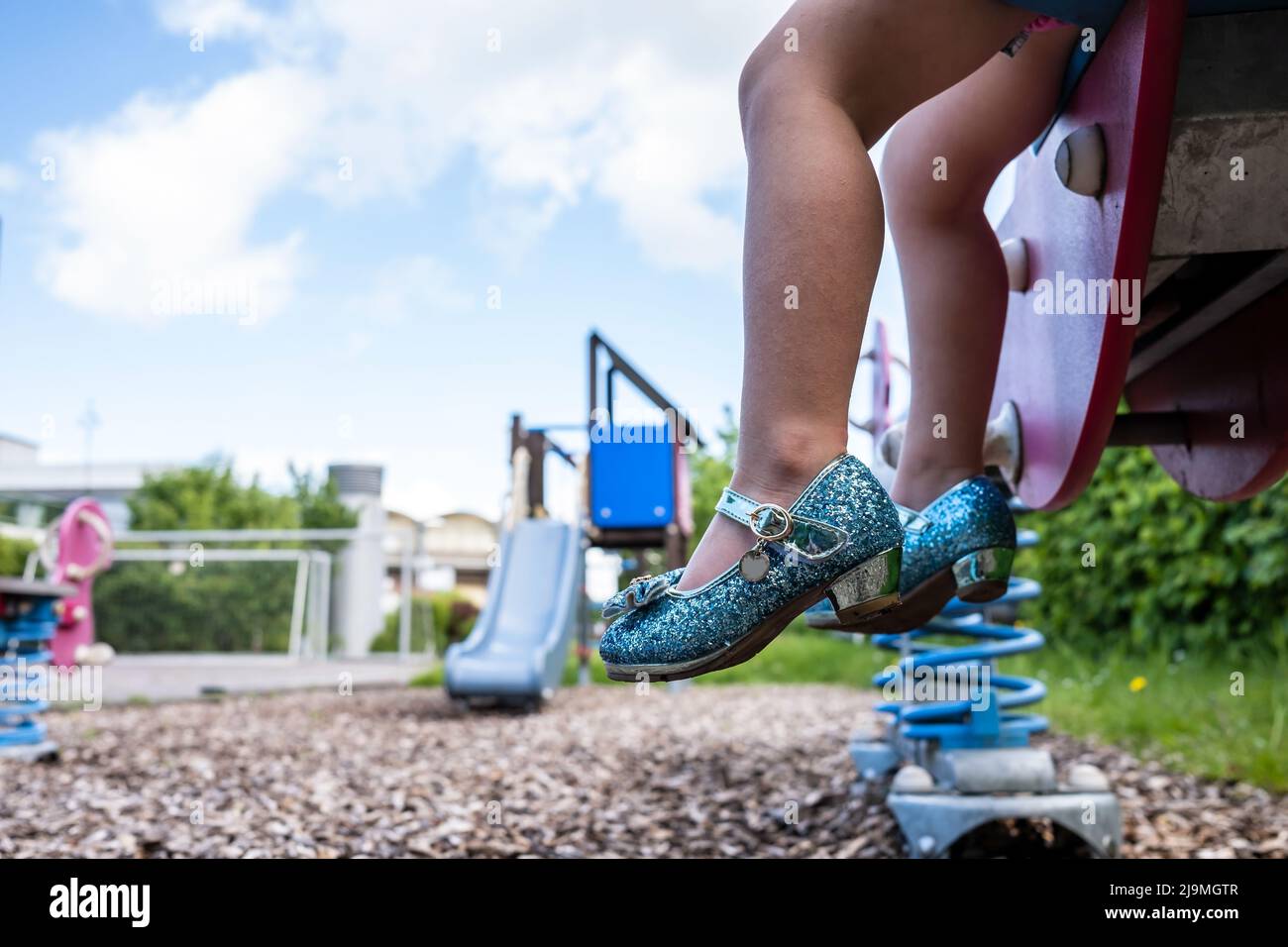 Feet of a child in beautiful high heeled shoes sit and rest on a swing ...