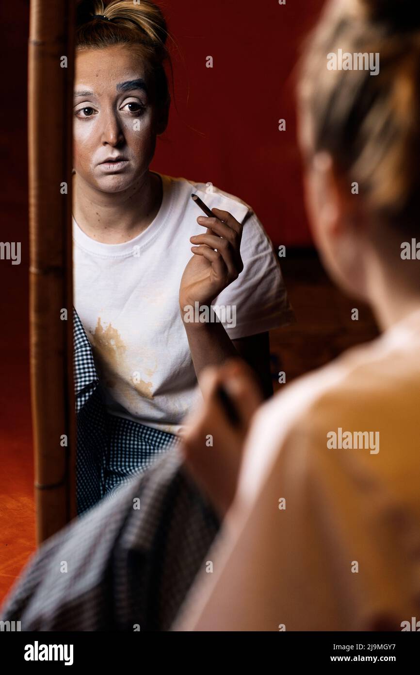 Young professional female mime in casual clothes painting the eyebrows ...