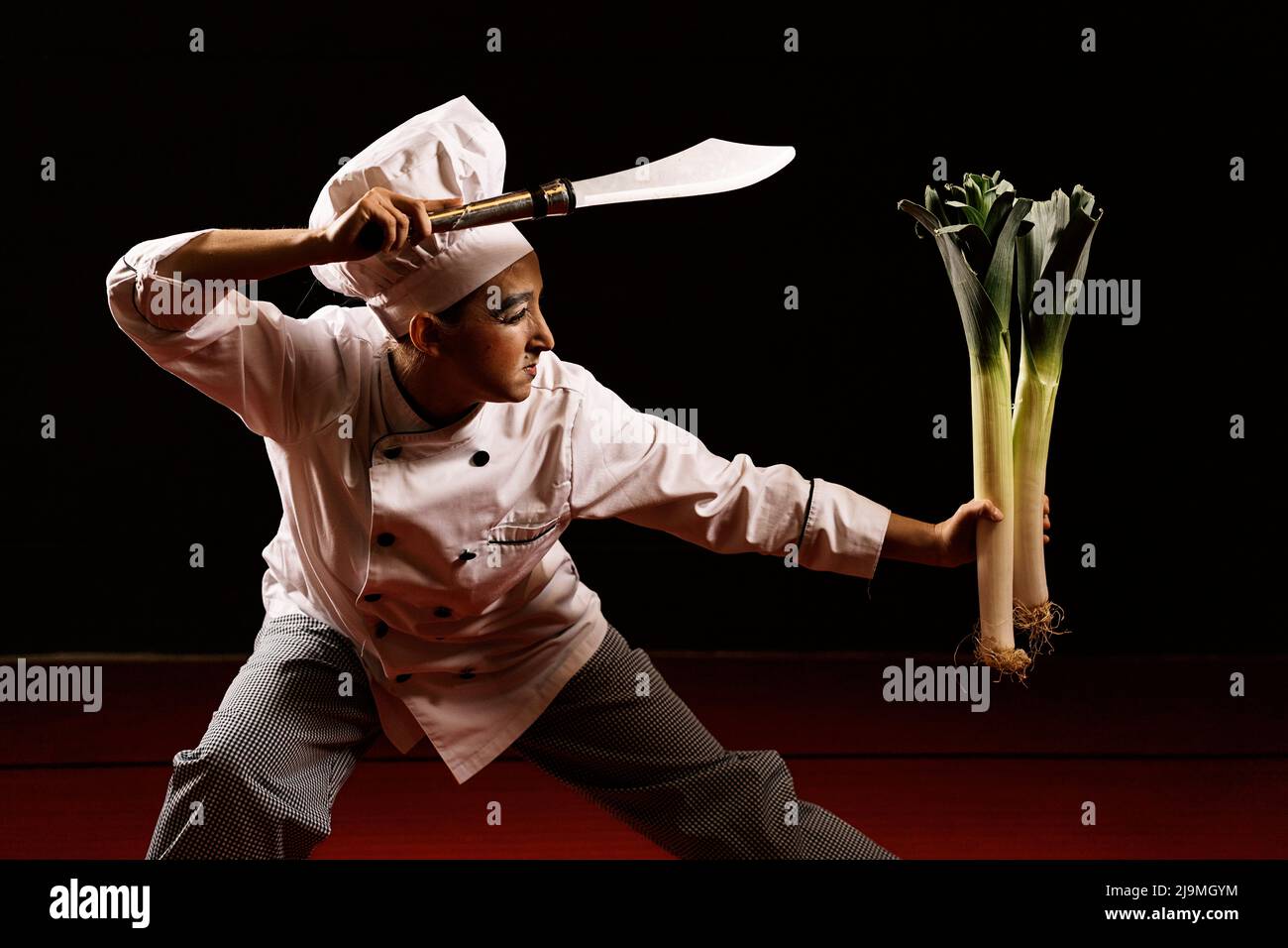 Funny young female clown in chef costume with makeup doing martial arts ...