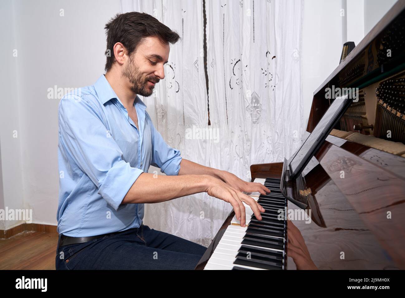 Side view of focused male musician playing piano while practicing from ...