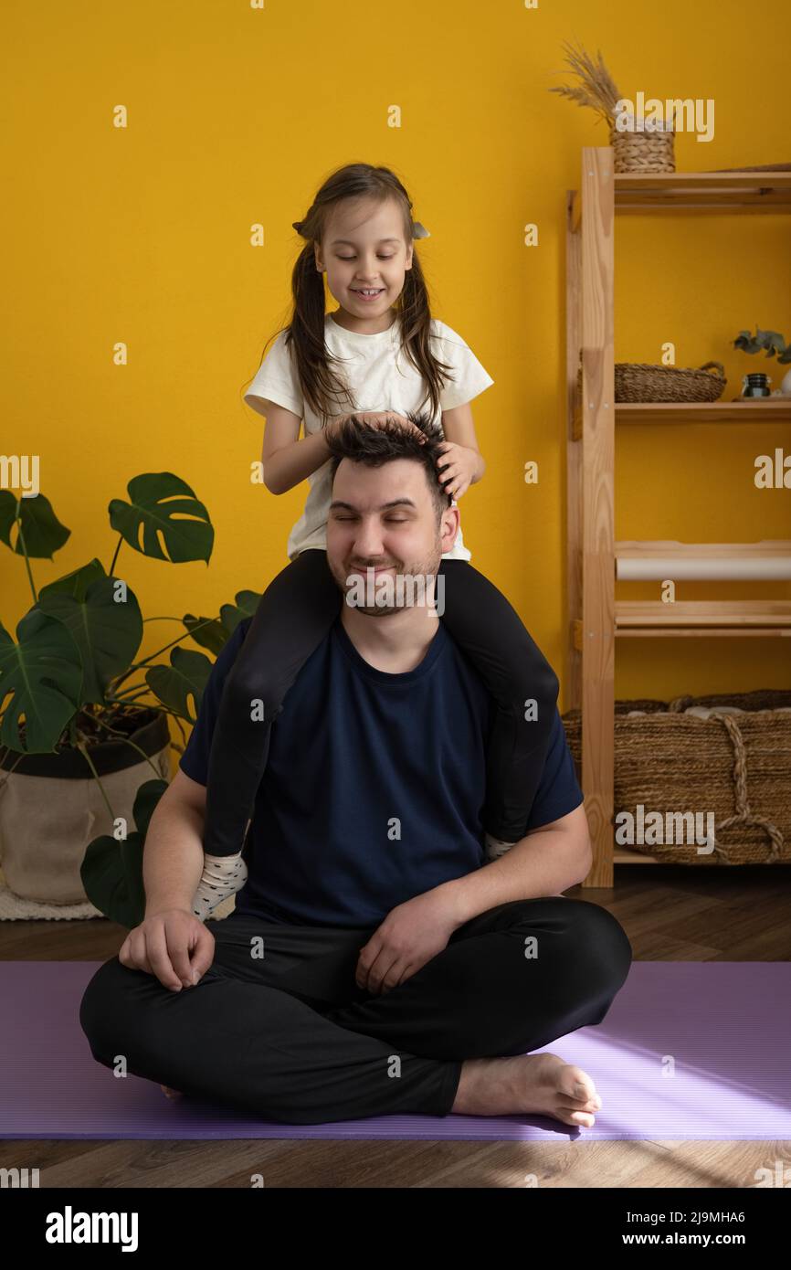 Happy girl smiling and rumpling hair of glad father while sitting on ...