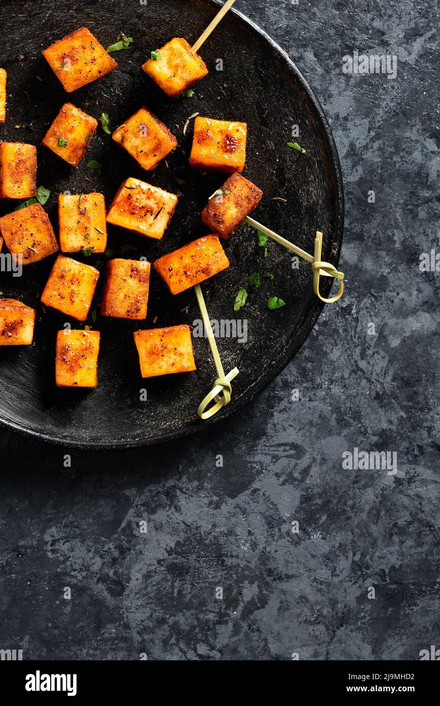 Indian roasted cottage cheese bites on plate over blue stone background ...