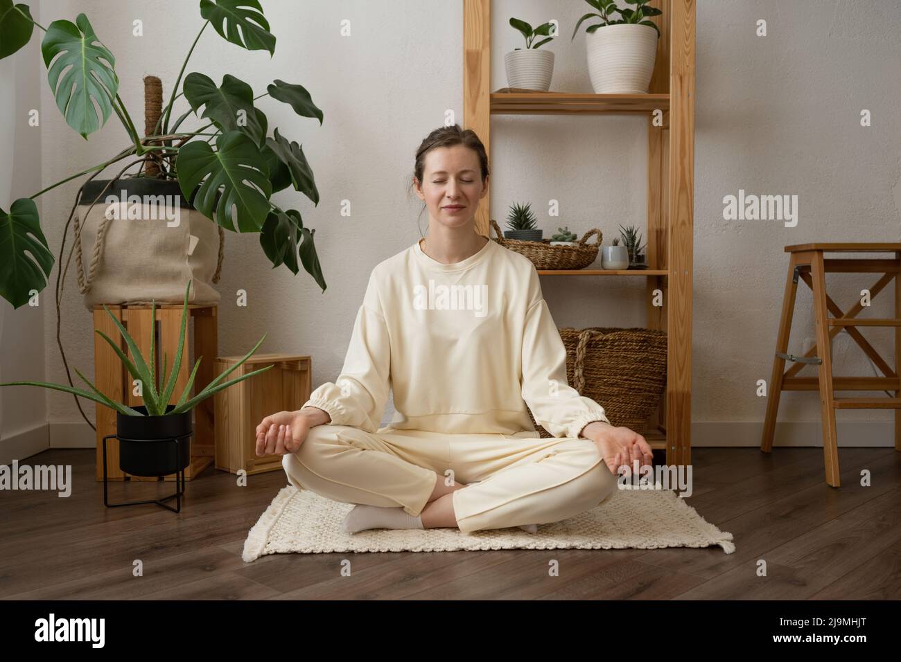 Full body of calm young female in comfy clothes meditating with closed ...