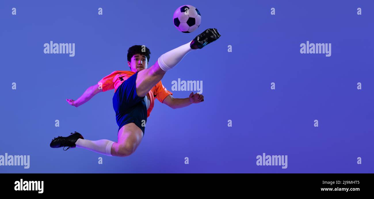 Studio shot of male professional football, soccer player practicing ...