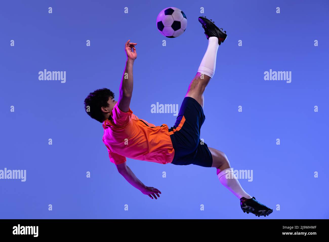 Studio shot of male professional football, soccer player practicing ...