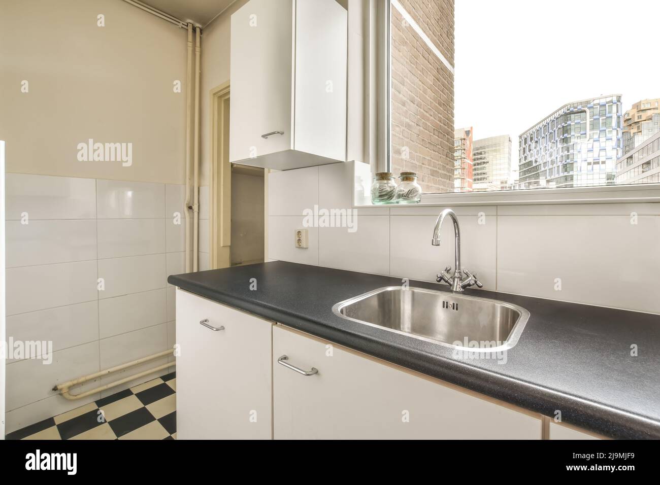 Counter with white cupboards and sink placed in light kitchen in ...