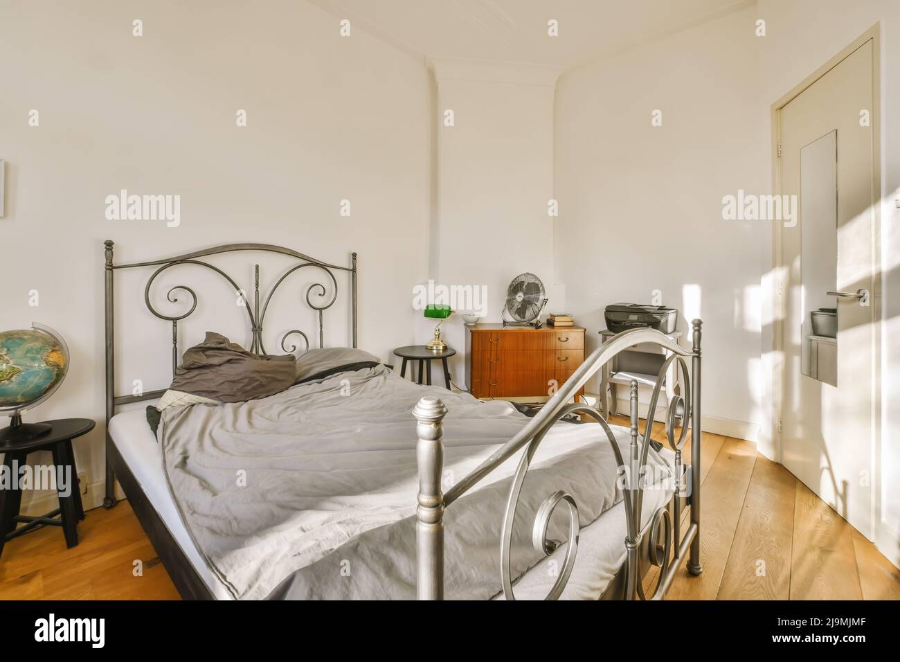 Wooden vintage commode near comfortable bed with blanket placed near ...