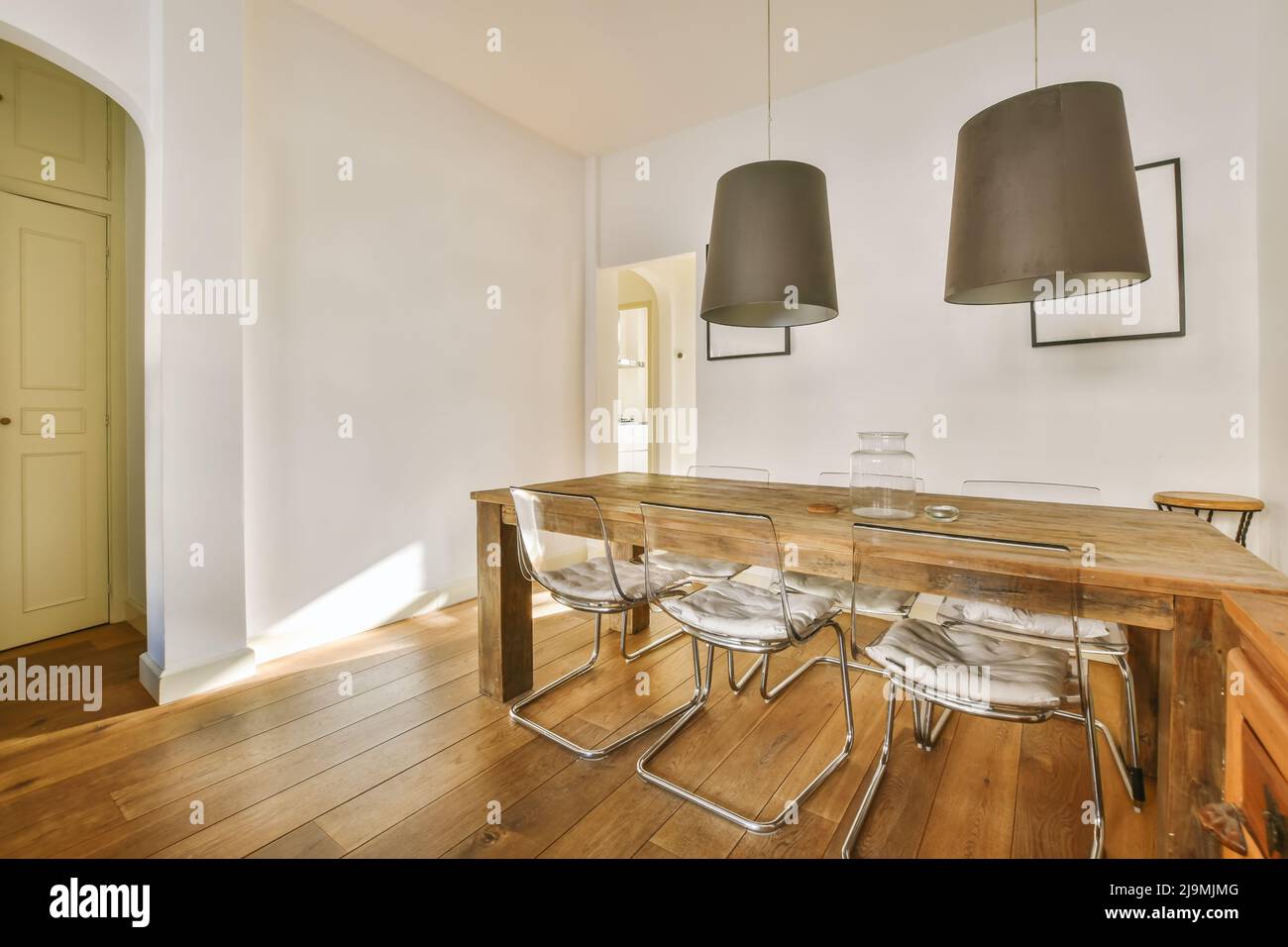Wooden dining table with see through chairs and lamp place in light ...