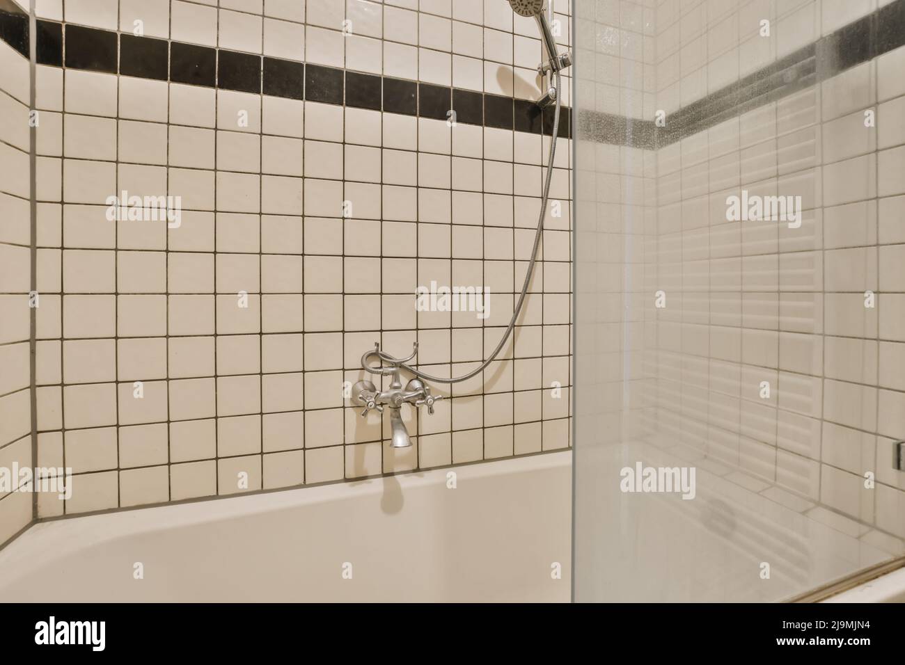Shiny chrome faucet of shower above ceramic bathroom in modern bathroom ...