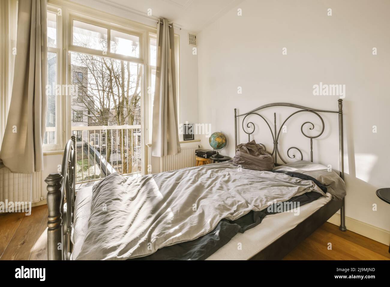 Metal frame bed bed with blanket placed near radiator in light bedroom ...