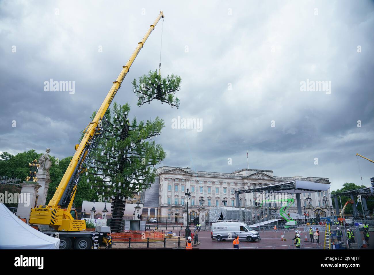 Construction workers use a crane to lift the top section of the Queen's ...