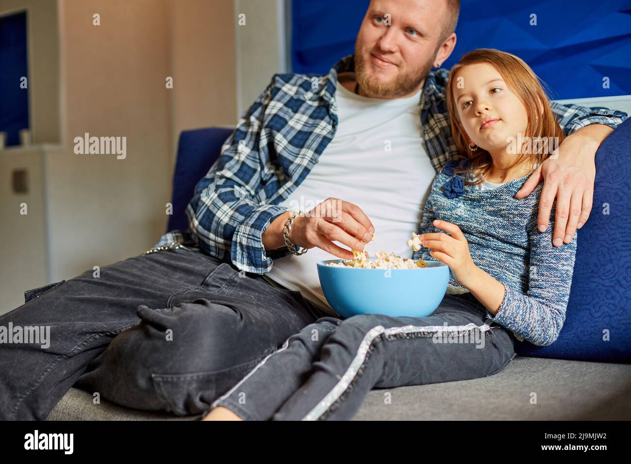 Father and daughter eat popcorn and watch TV film, Dad and child girl ...