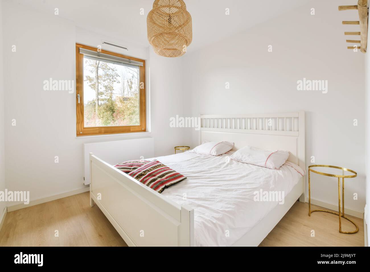 Comfortable bed with chrome glass bedside table located against window ...