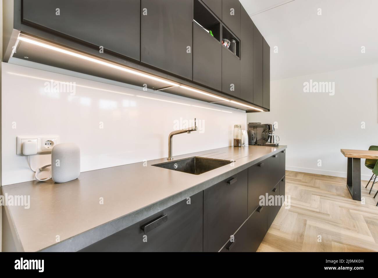 Sink and tap installed on counter under black cupboards inside ...